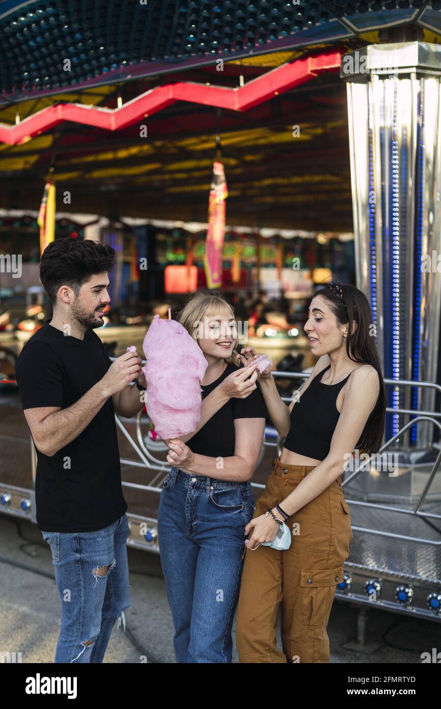 Group of friends eating cotton candy and having fun at an amusement ...