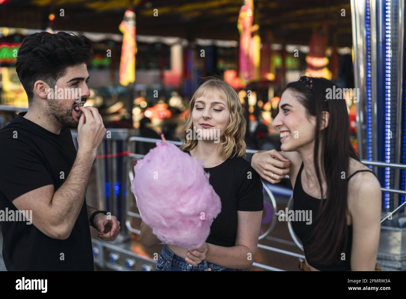 Group of friends eating cotton candy and having fun at an amusement ...