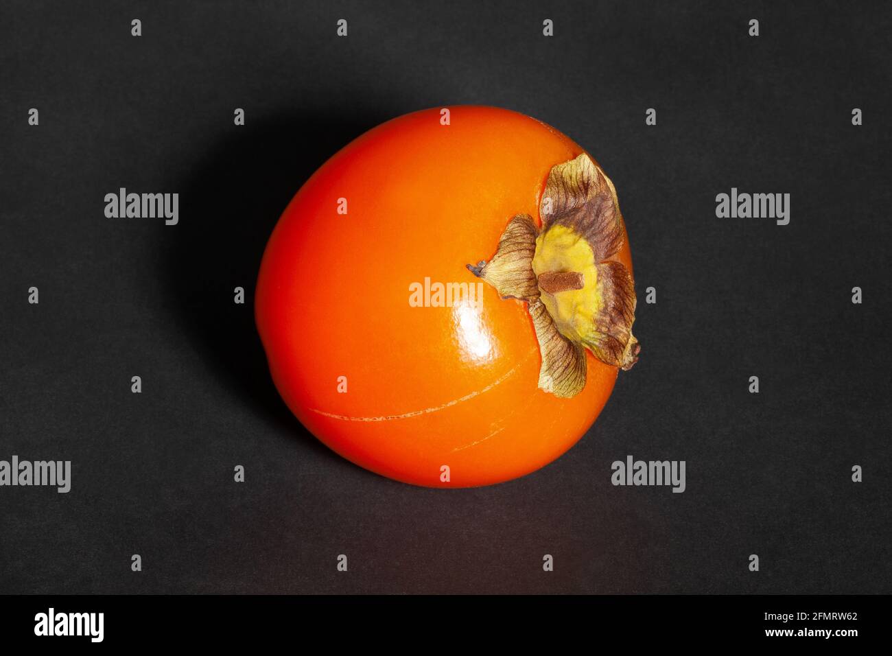 single persimmon on black background Stock Photo - Alamy