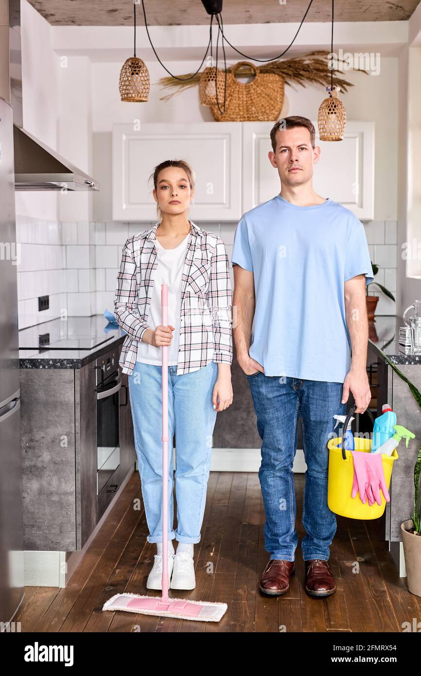 Young janitors man and woman standing at home before housekeeping ...