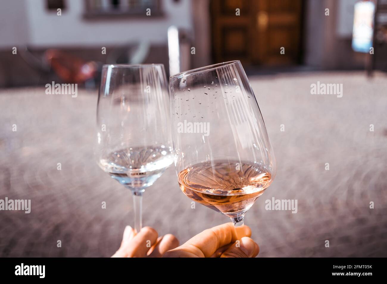 Two people toasting each other outdoors with two glasses of wine, rose ...