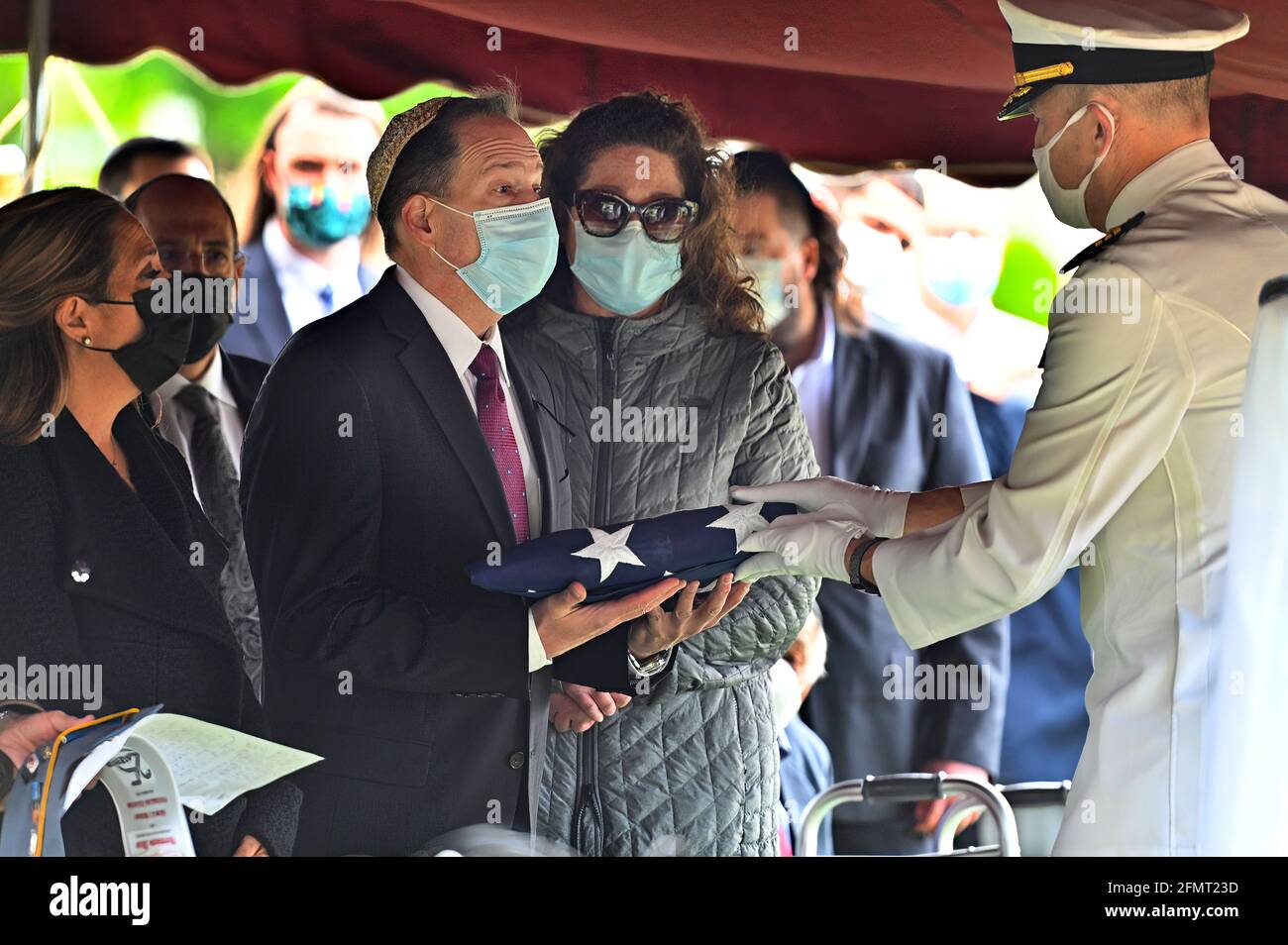 A masked navy service member hands the family of WWII Veteran Sam ...