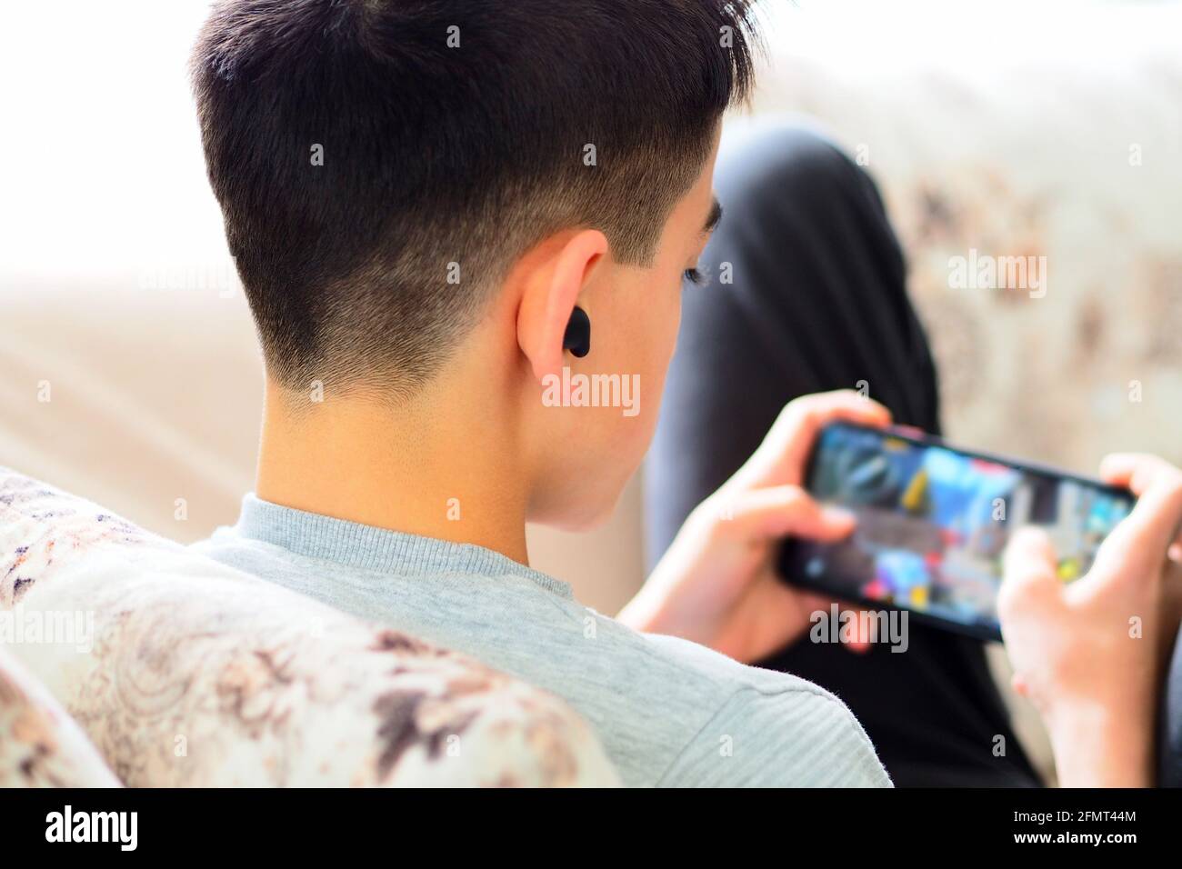 a teenager playing a game with a cell phone, Phone addiction in the z ...