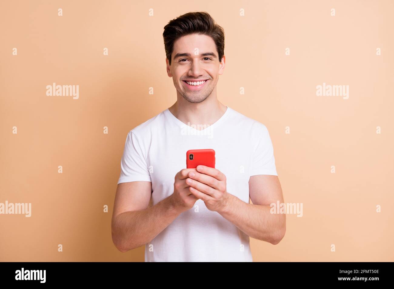 Portrait of friendly young man hold phone toothy smile look camera ...