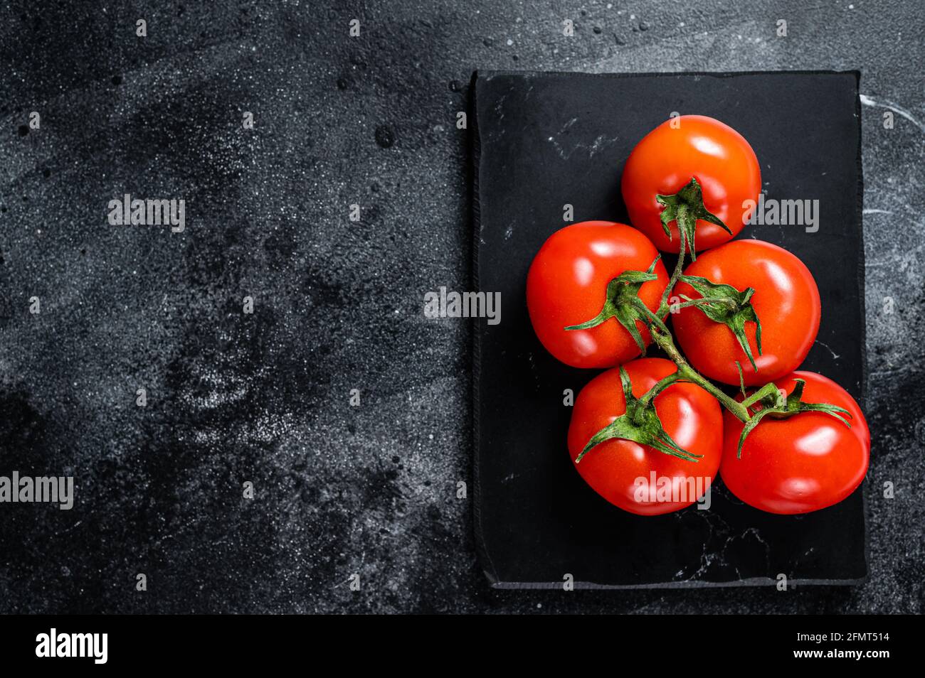 Branch of Red cherry tomatoes on marble board. Black background. Top ...