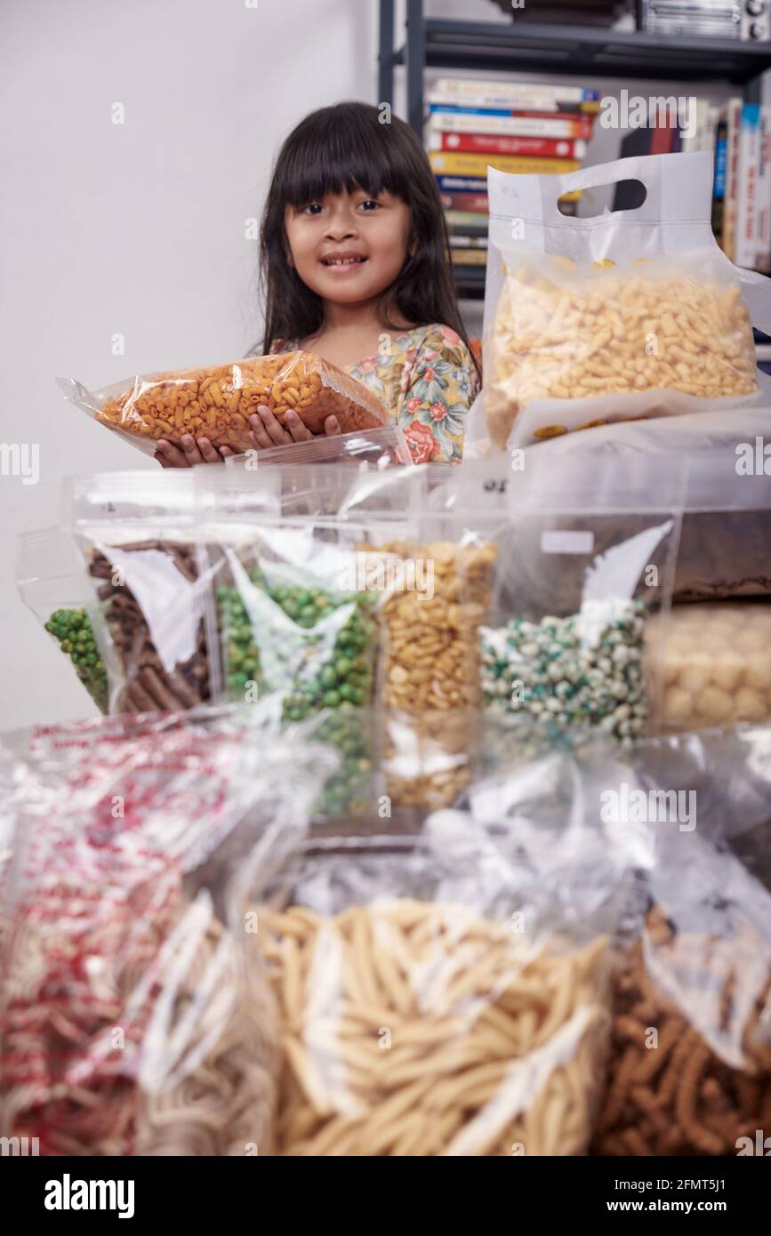 Cute little girl selling many varieties of snack at home Stock Photo ...