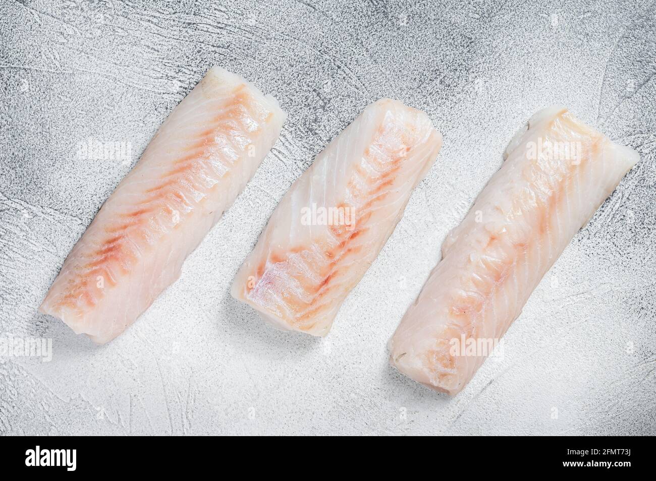 Raw Norwegian cod fish fillet on kitchen table. White background. Top ...