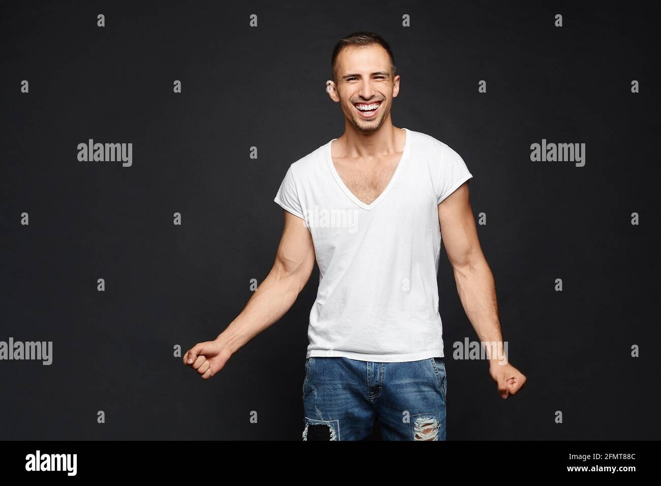 Happy guy in white t-shirt isolated at dark background. A handsome ...
