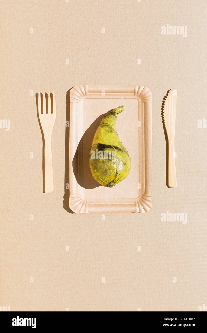 Pear wrapped in polyethylene plastic on the beige paper background ...