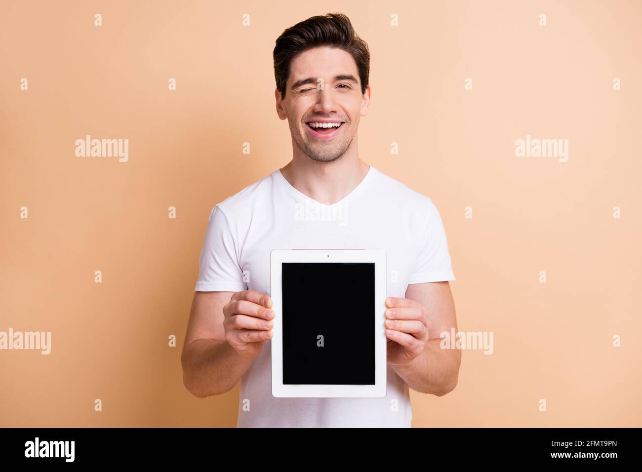 Portrait of funny friendly man arms hold tablet showing display eye ...