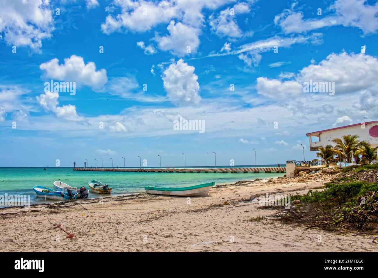 Beach in Mexico with Pier and building in distance and fishing boats ...