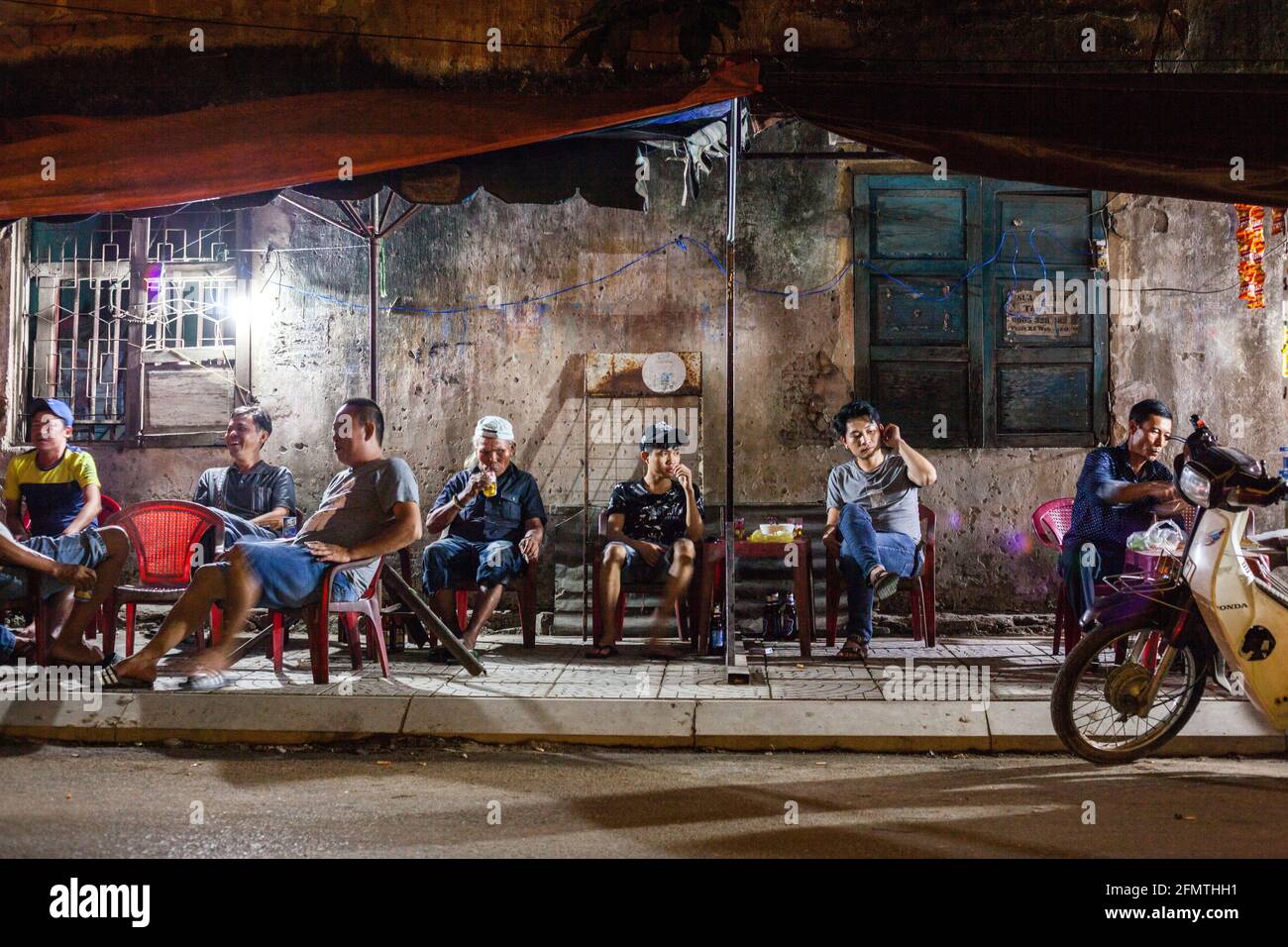 A group of Vietnamese males seated at ambient roadside pavement cafe ...