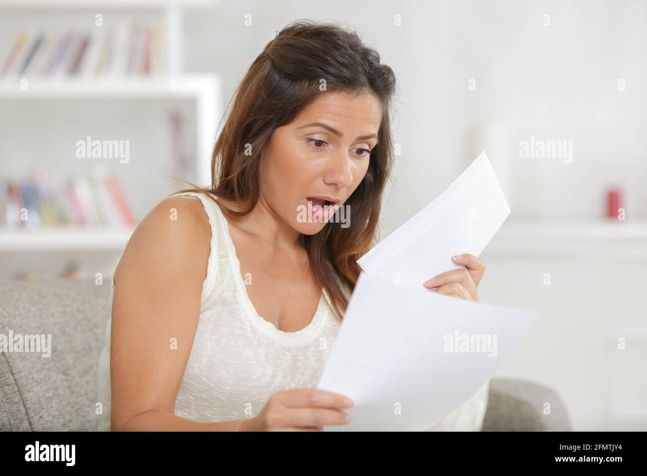 woman reading a letter with a shocked expression Stock Photo - Alamy