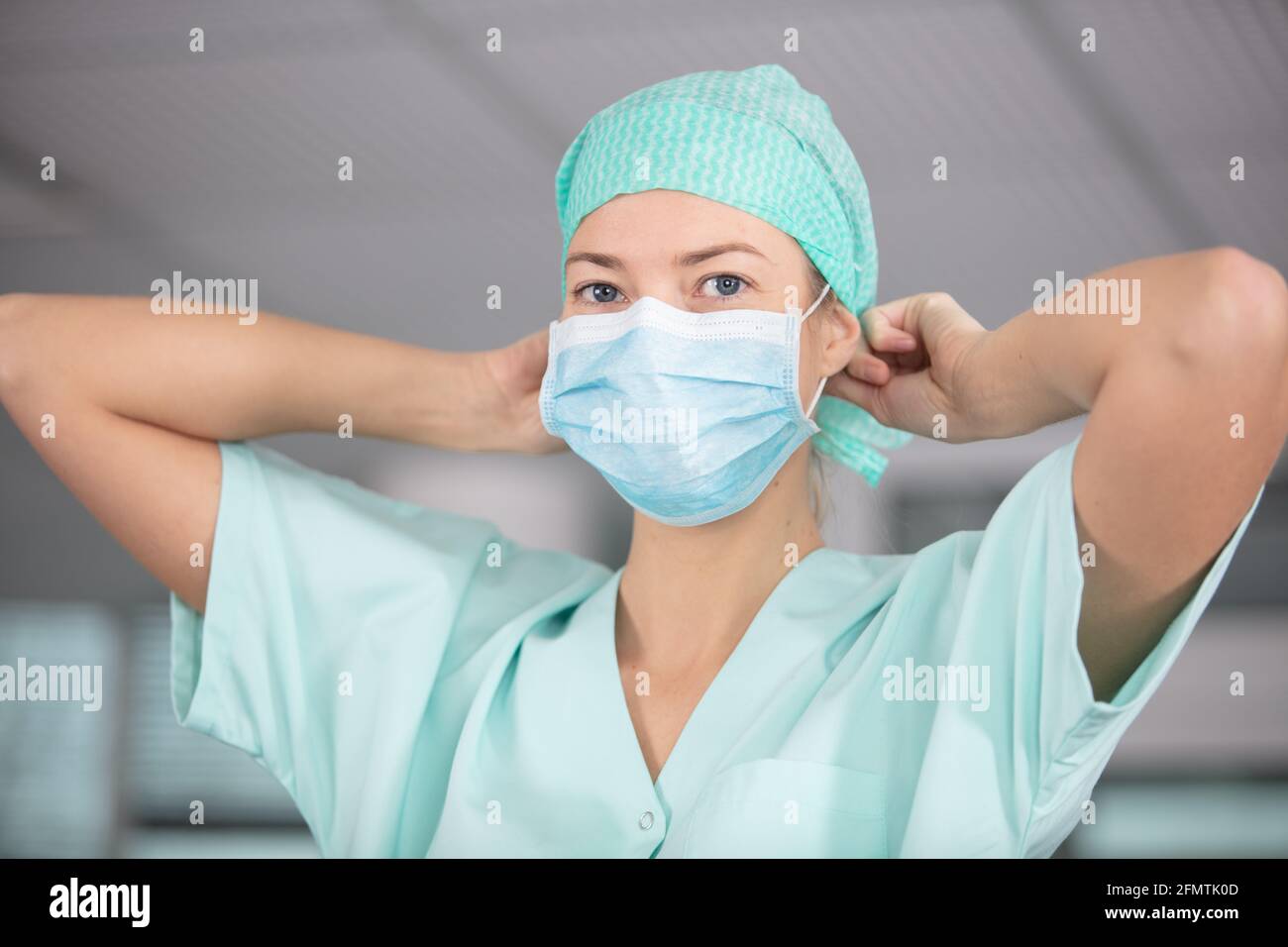 female nurse in scrubs securing her facial mask Stock Photo - Alamy