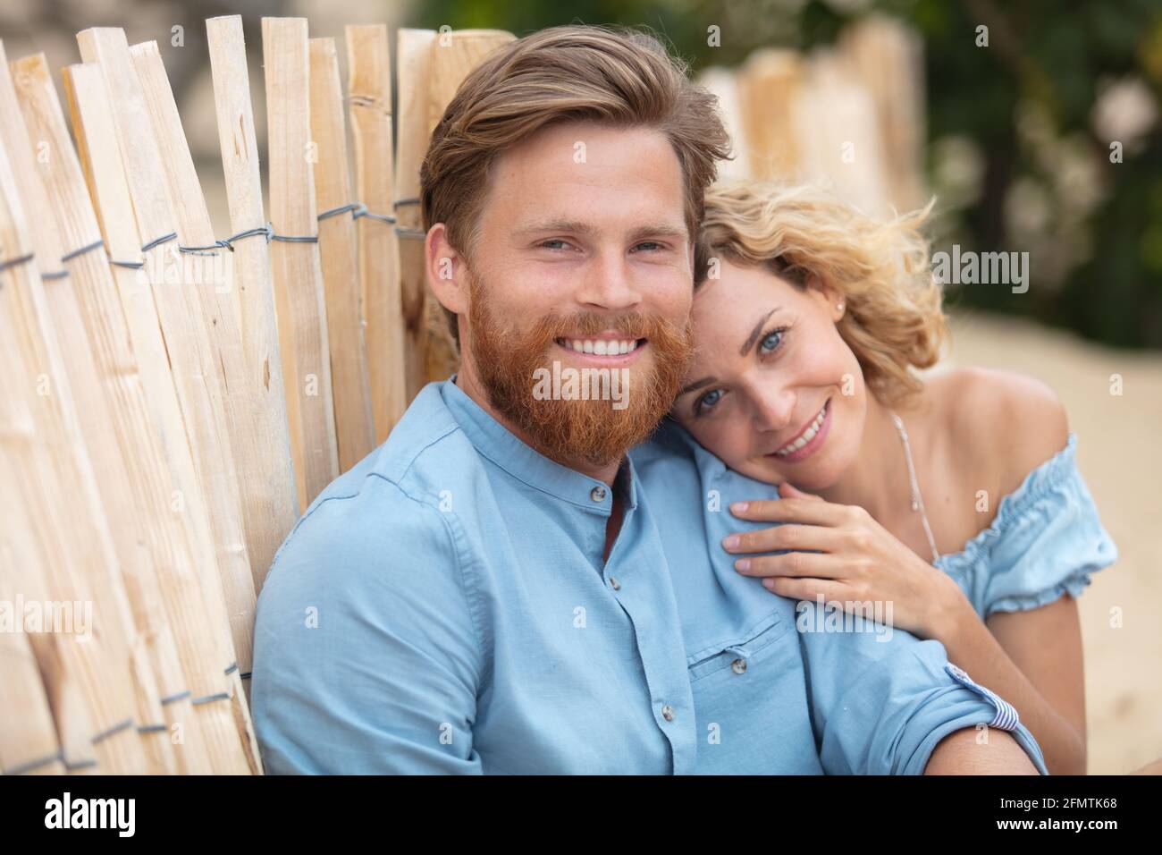 couple are sitting by the wooden fence on the beach Stock Photo - Alamy