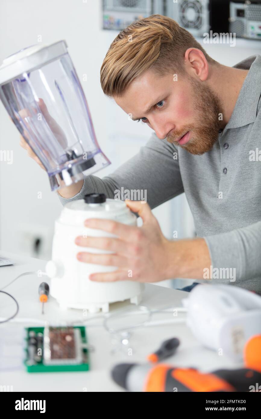 man sitting by desk repairing blender mixer Stock Photo - Alamy