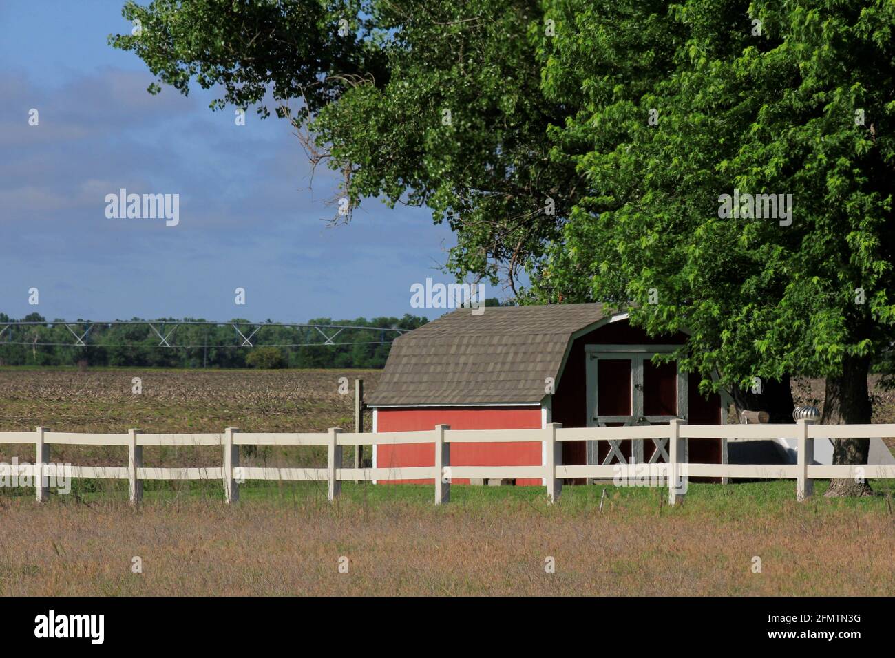 Kansas red and white barn with a fence and tree's with blue sky out in ...