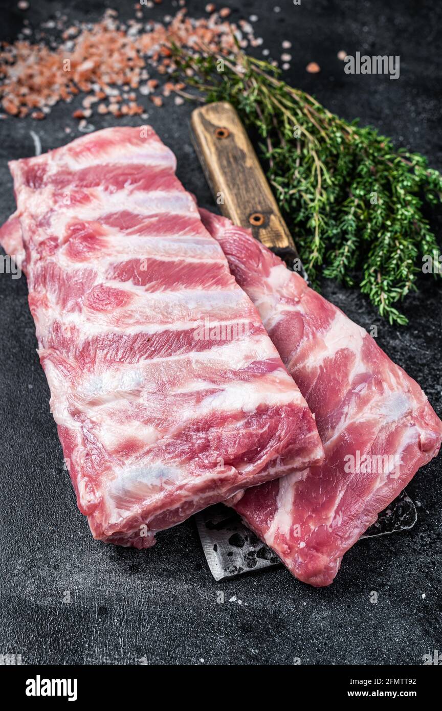 Uncooked Raw pork spare ribs on butcher meat cleaver. Black background ...