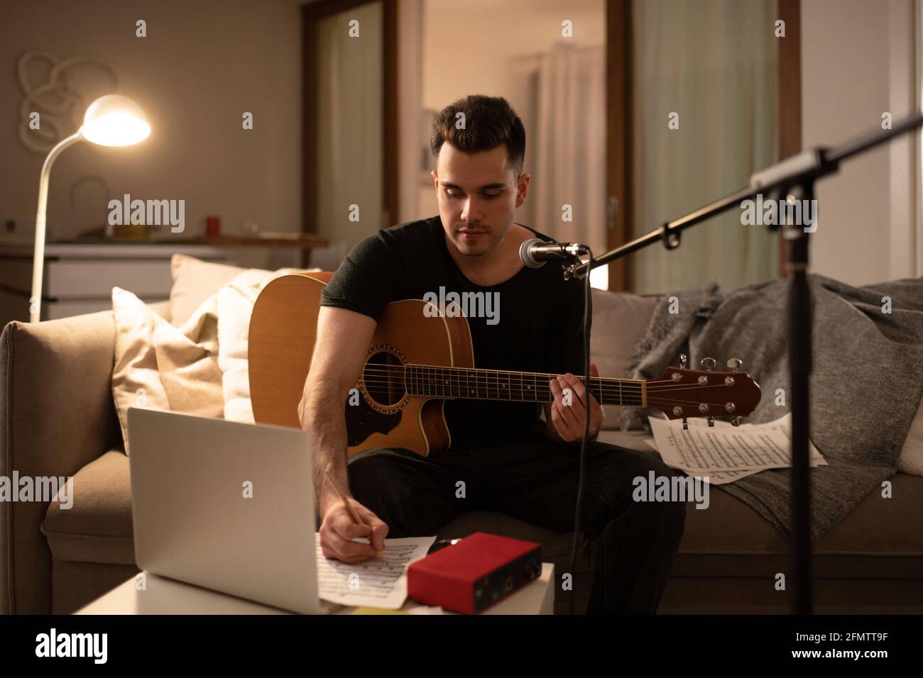 Male guitarist writing song at home Stock Photo - Alamy