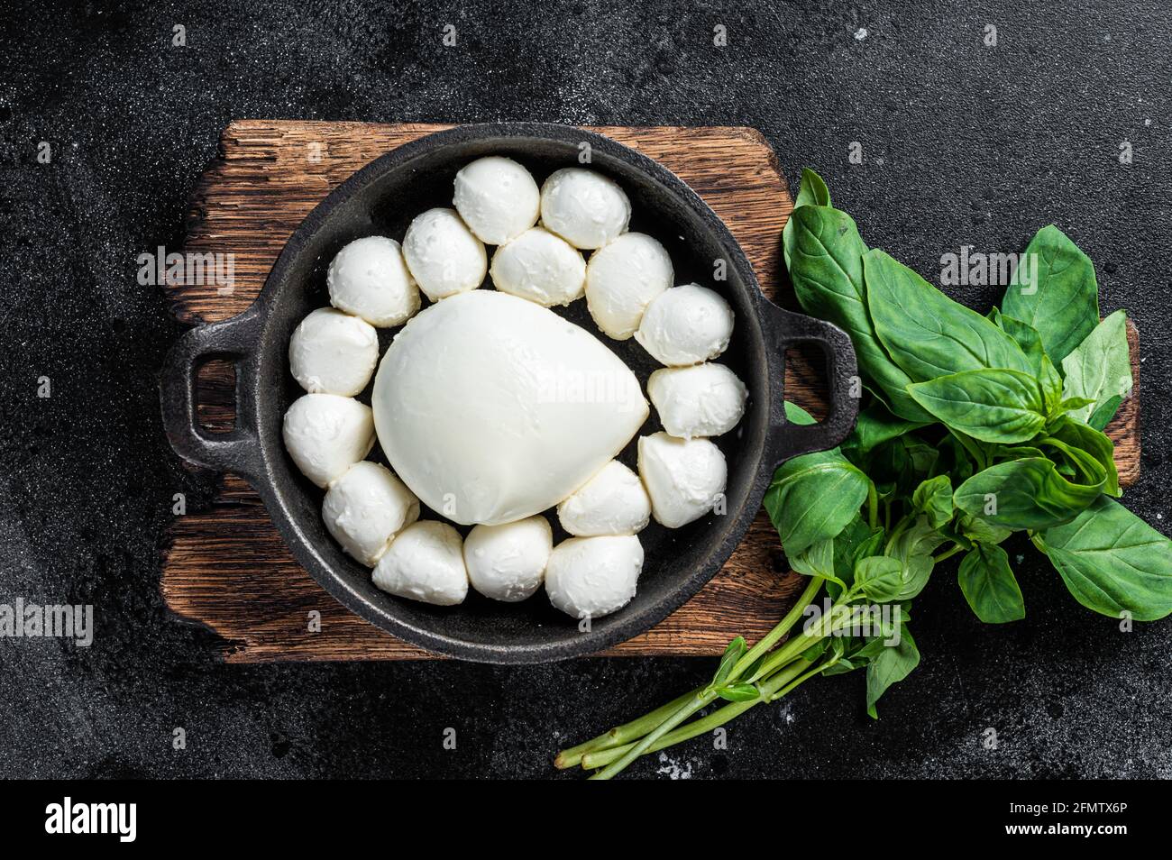 Mozzarella cheese mini balls in pan with basil. Black background. Top ...