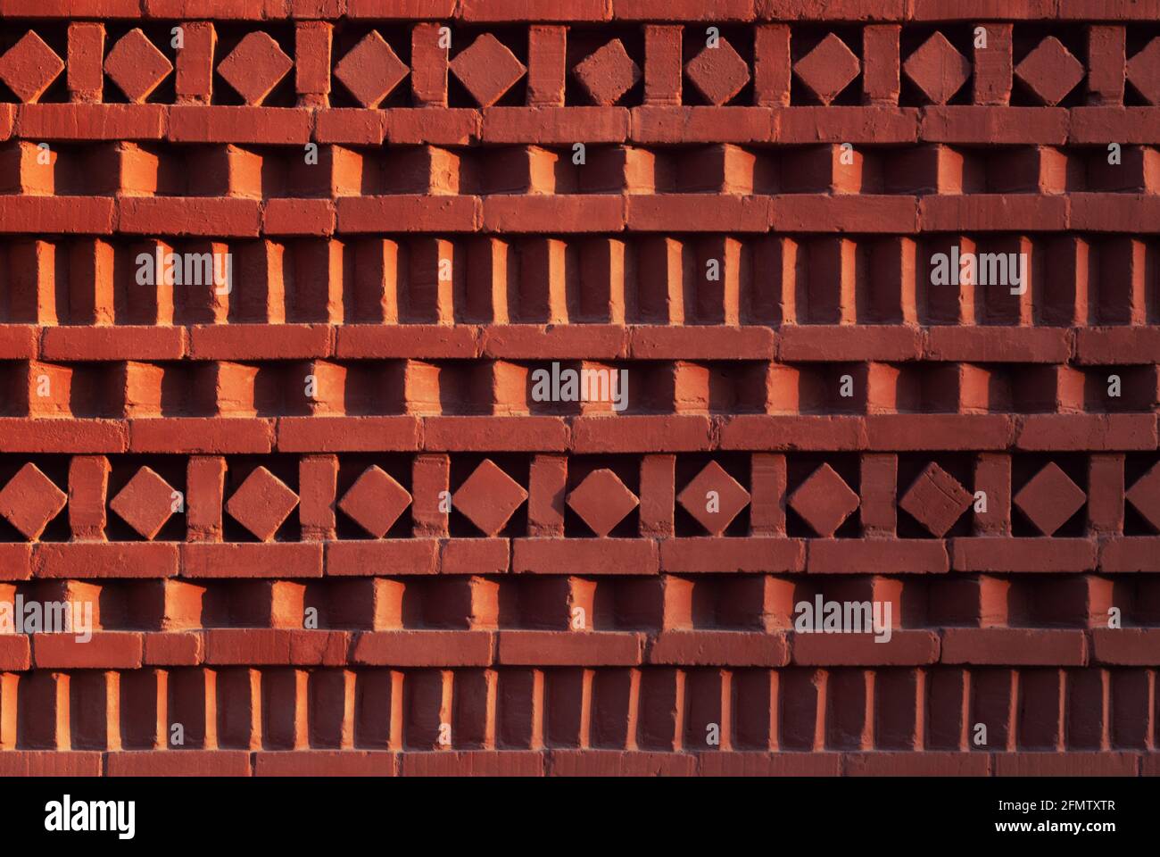Red brick wall with ornamental pattern in shadow and light gradient ...