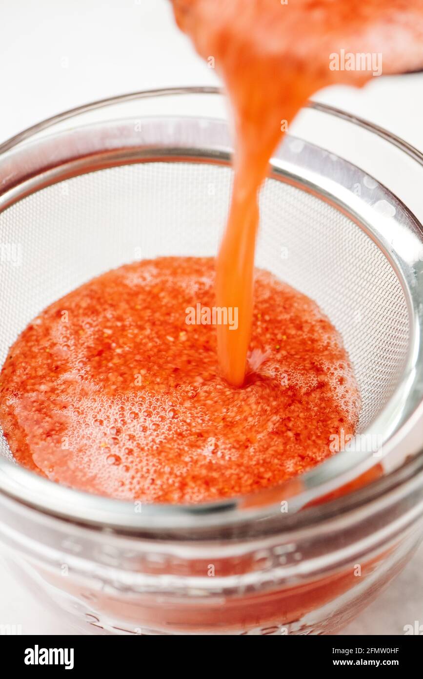 Pouring strawberry puree through a strainer Stock Photo - Alamy