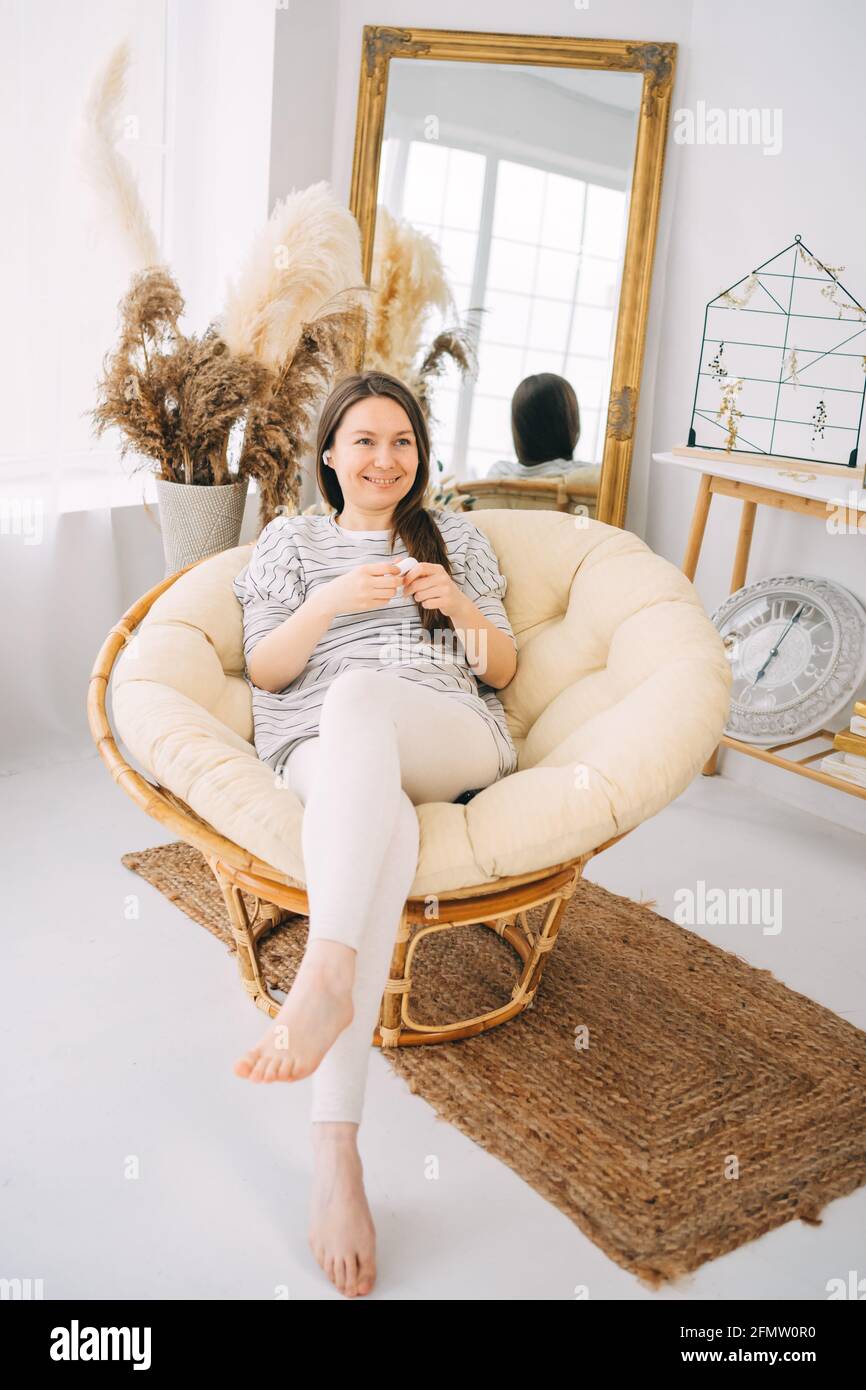 Beautiful girl listens to music in a chair Stock Photo - Alamy