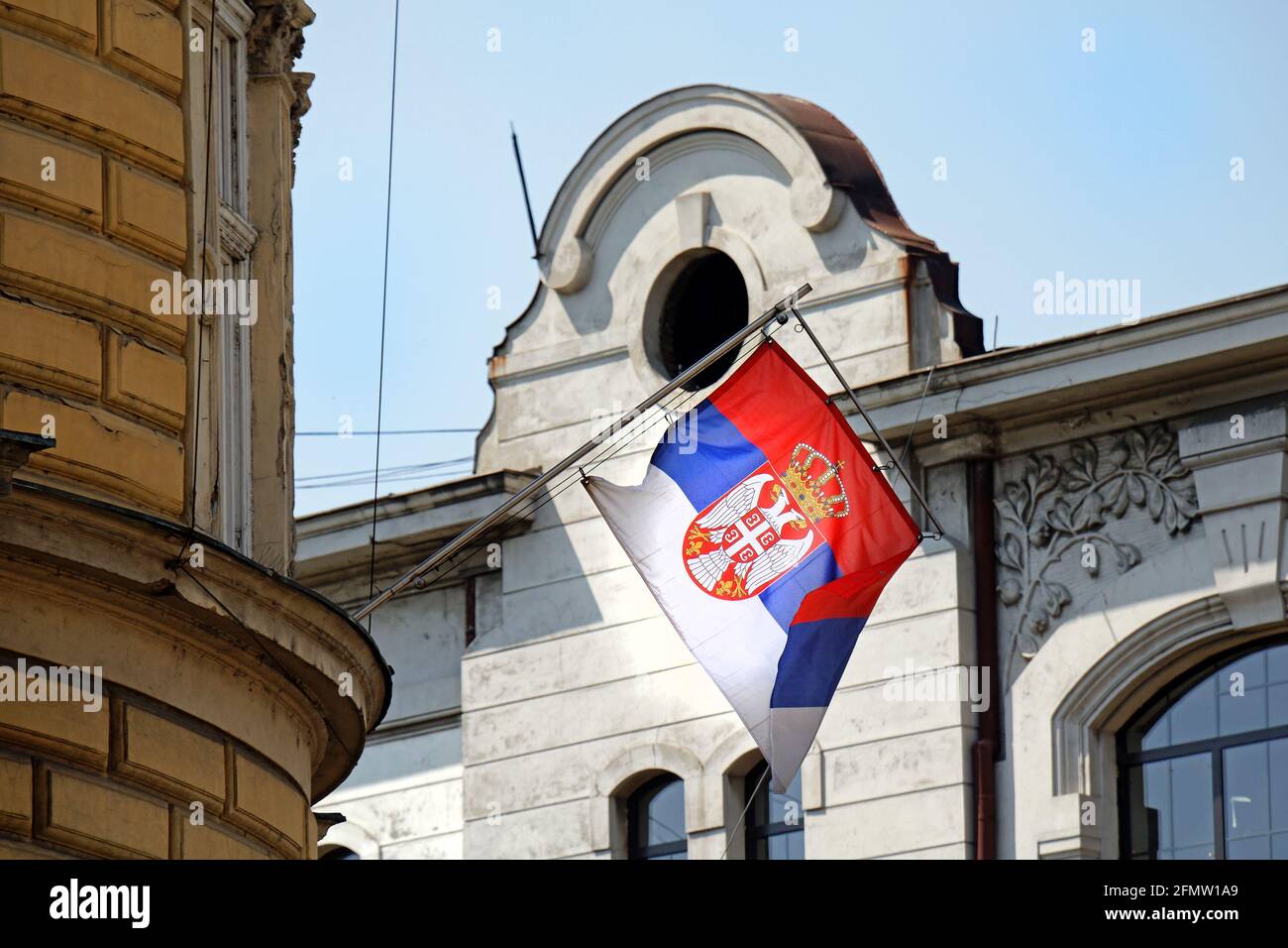 Serbian flag hanging on building facade on wind Stock Photo - Alamy