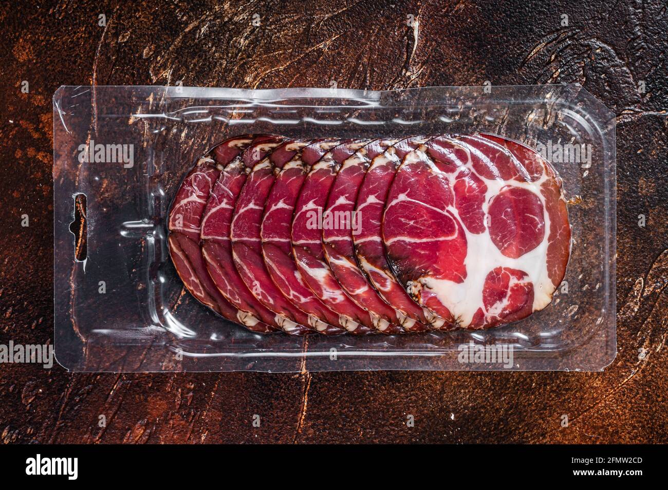 Italian sliced cured coppa meat in vacuum packaging. Dark background ...