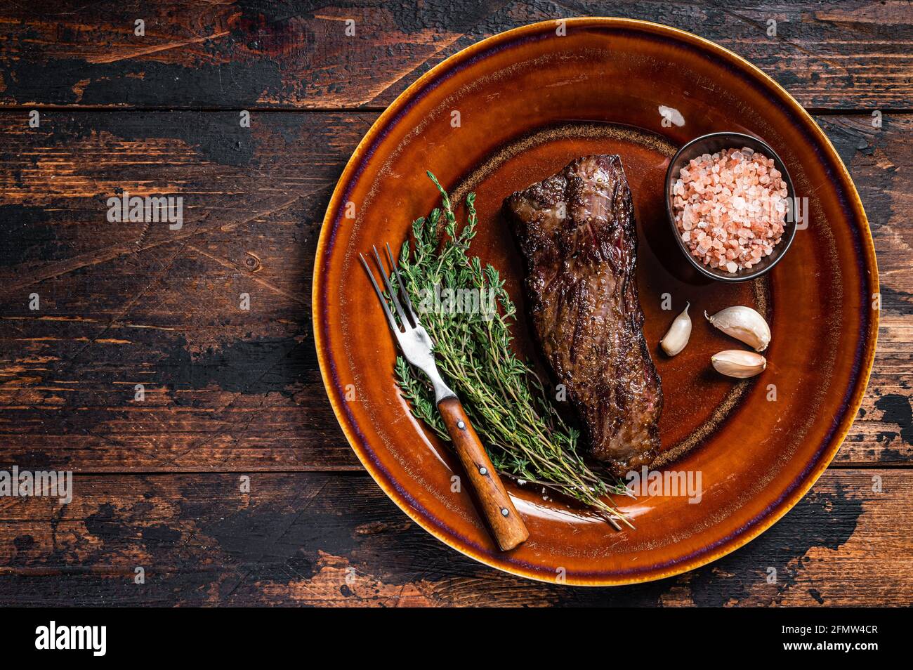 Grilled machete skirt beef steak on rustic plate with herbs and pink ...