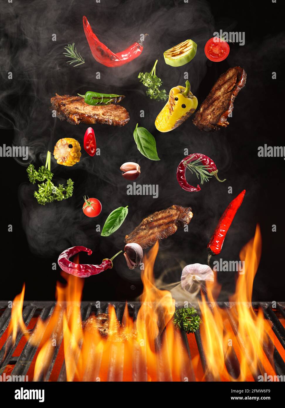 Flying beef stakes and vegetables above barbecue grill with fire on ...