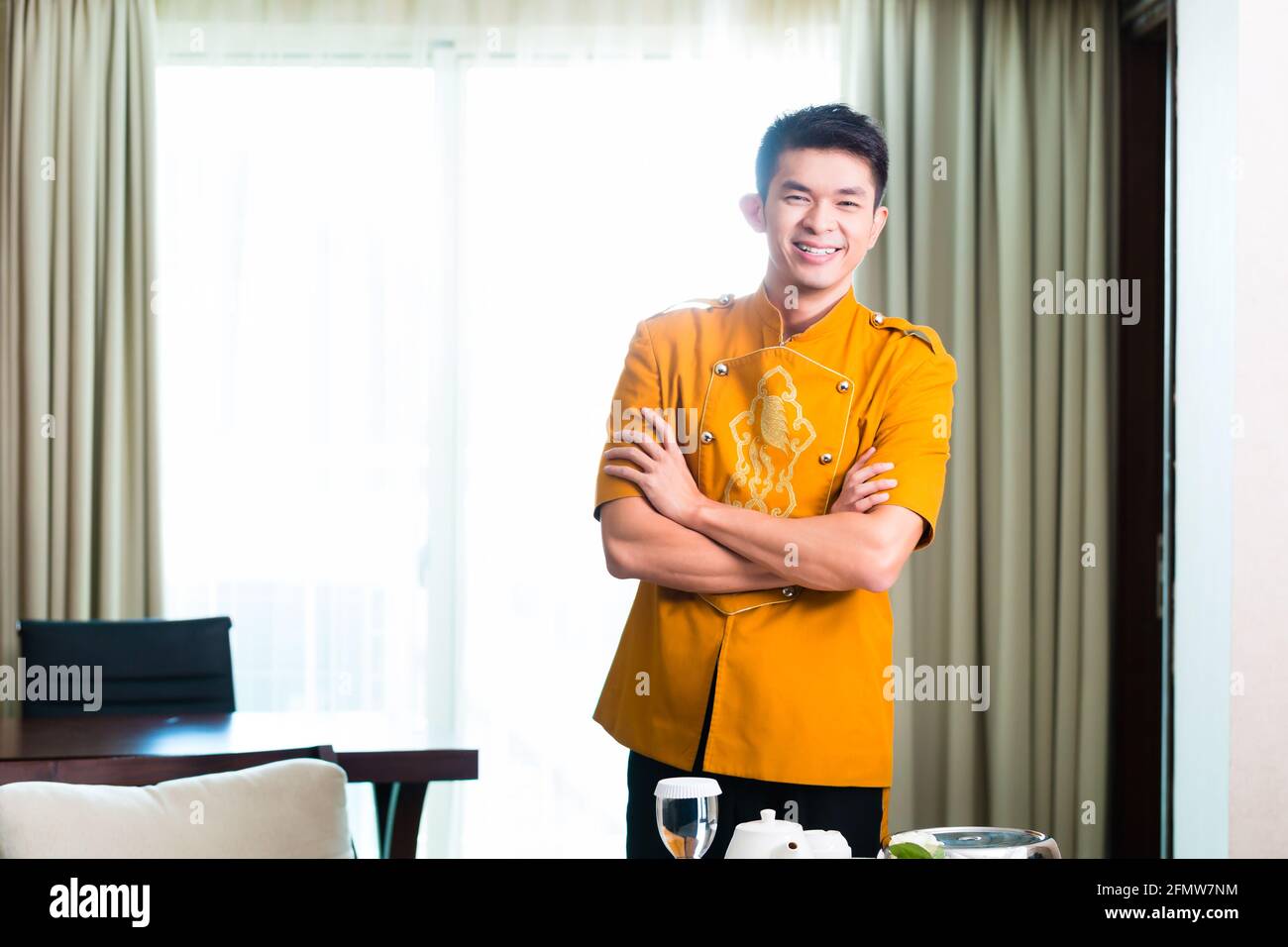 Asian Chinese room service waiter or steward serving guests food in a ...