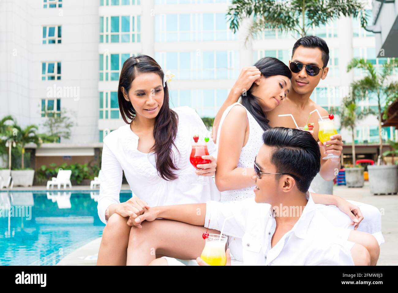 Asian couples sitting by hotel swimming pool Stock Photo - Alamy