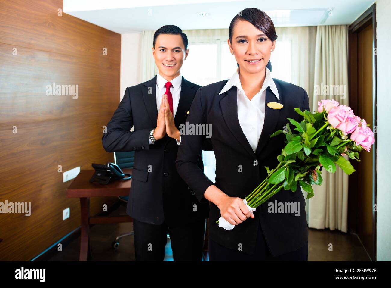 Portrait of hotel staff greeting with flowers Stock Photo - Alamy