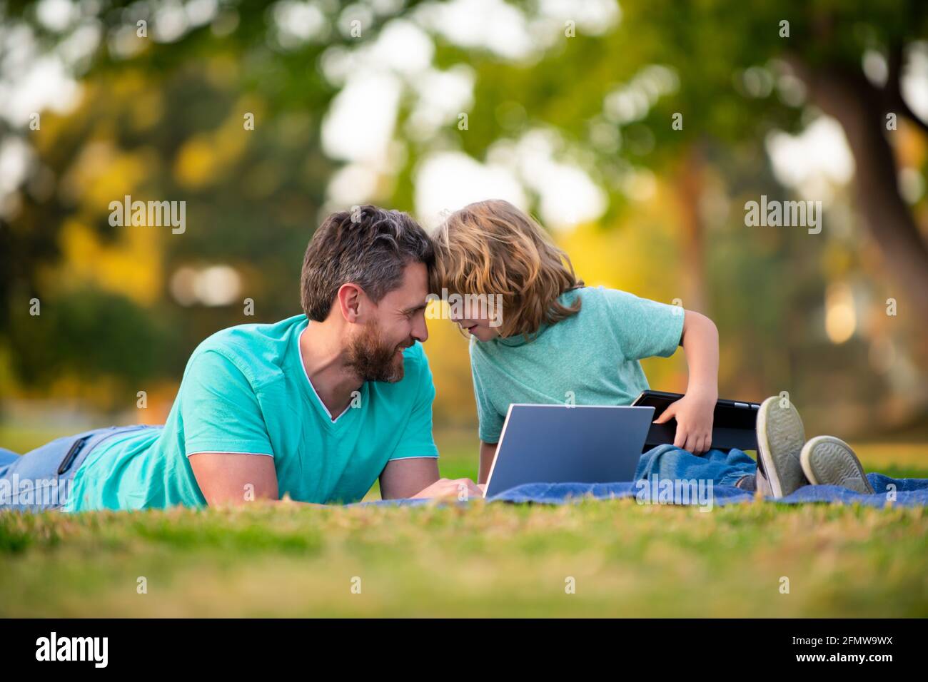 Happy father and son enjoying summer time on vacation in a sunny park ...