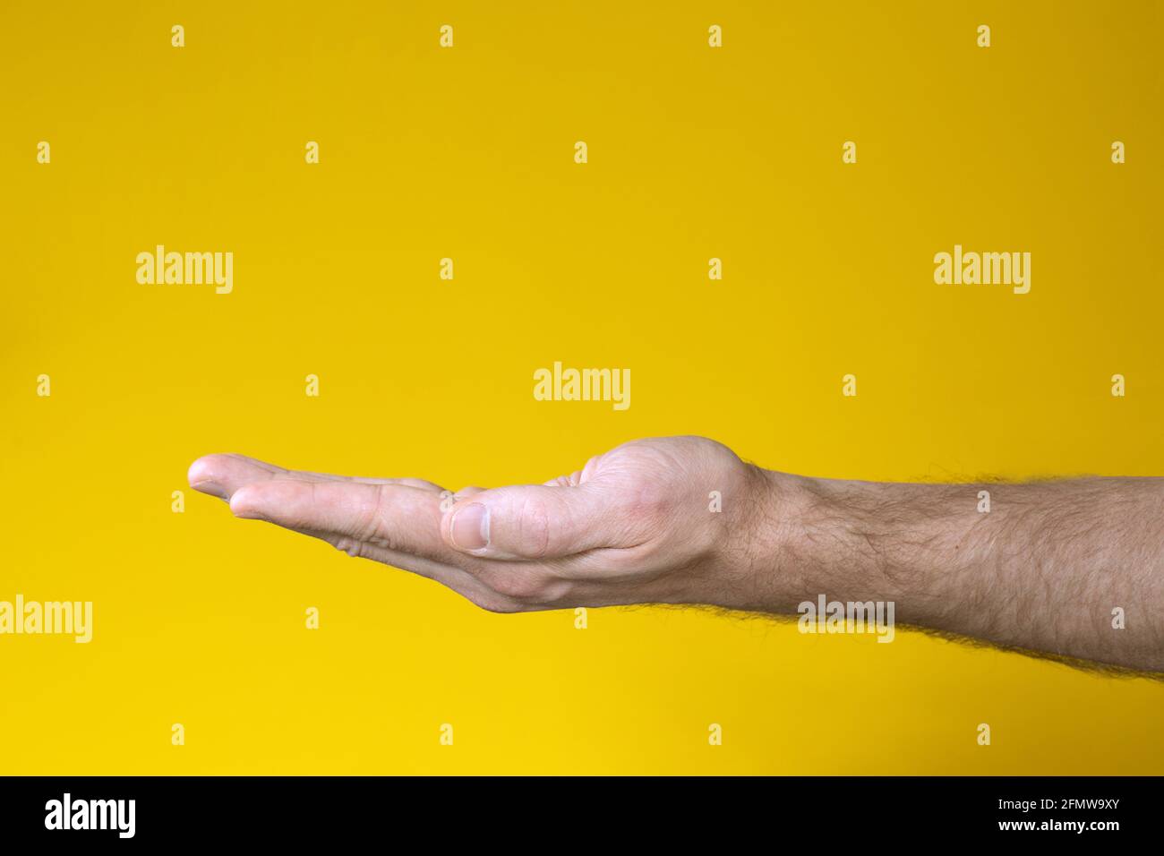 Man hand with palm facing up on yellow background. Gesture of asking or ...