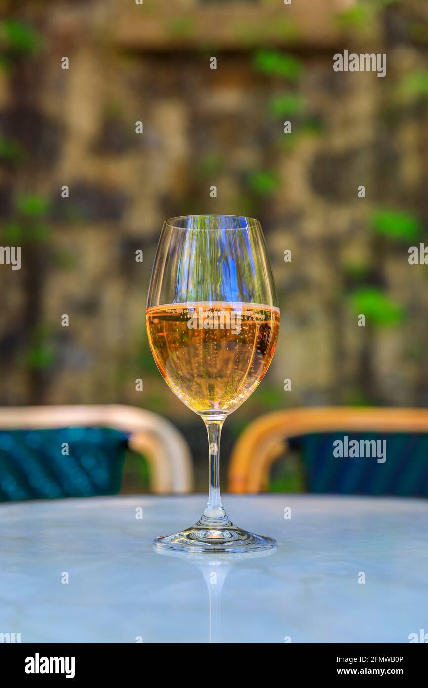 Glass of sparkling rose wine on an outdoor table with a blurred ...