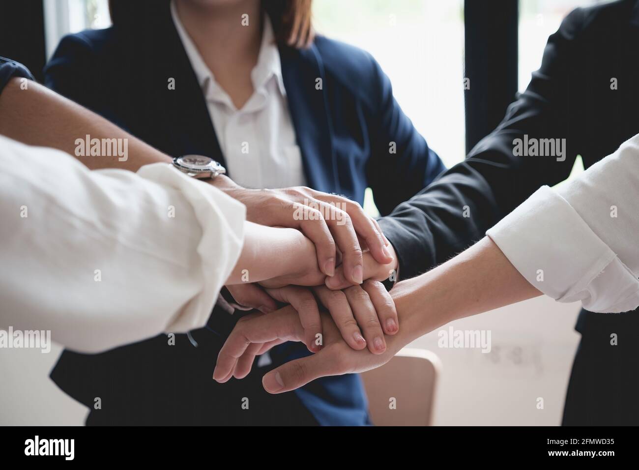 Business team putting their hands together gesture as they laugh and ...
