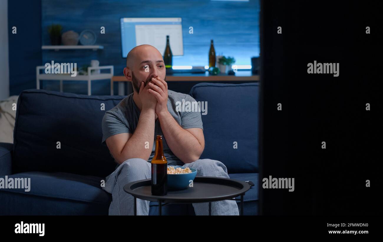 Emotional young guy watching disgusting tv program movie alone in ...