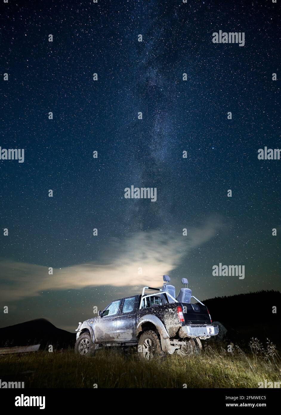 Illuminated pickup offroad truck in mud on mountain meadow at night ...