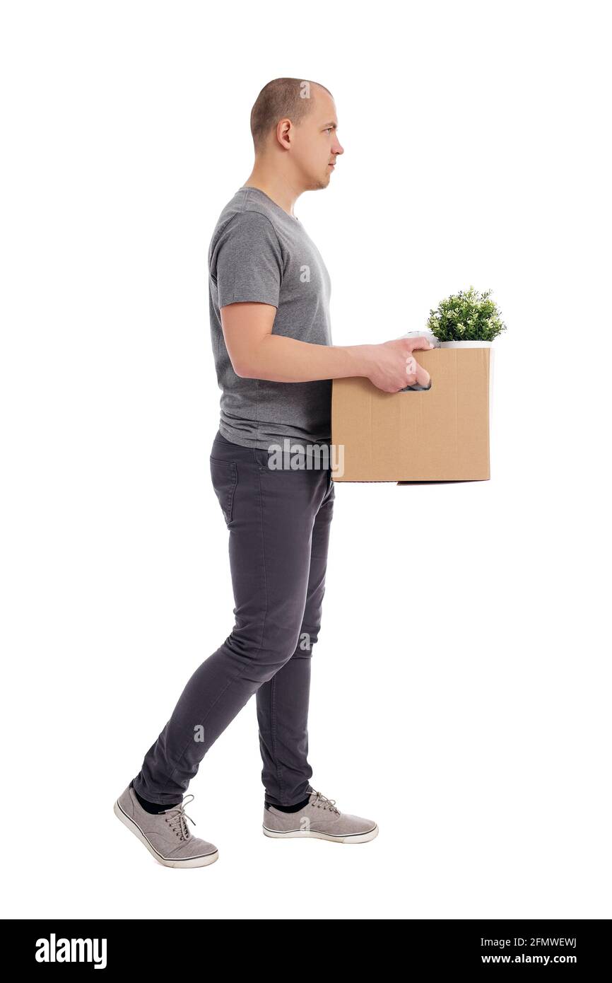 side view of young handsome walking man holding box with belongings ...