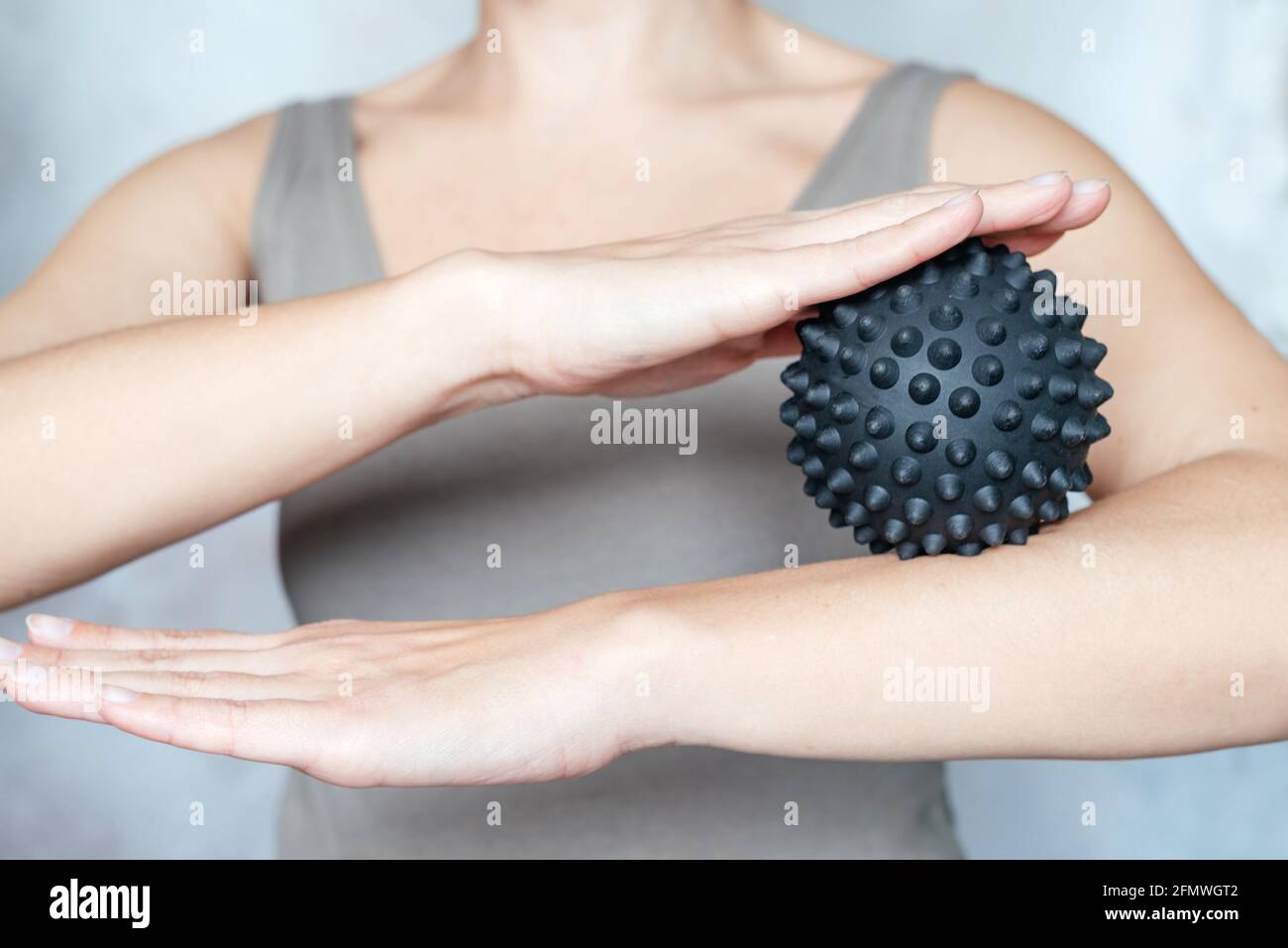 A woman holds a spiky trigger point massage ball used for muscle pain treatment and deep tissue ...