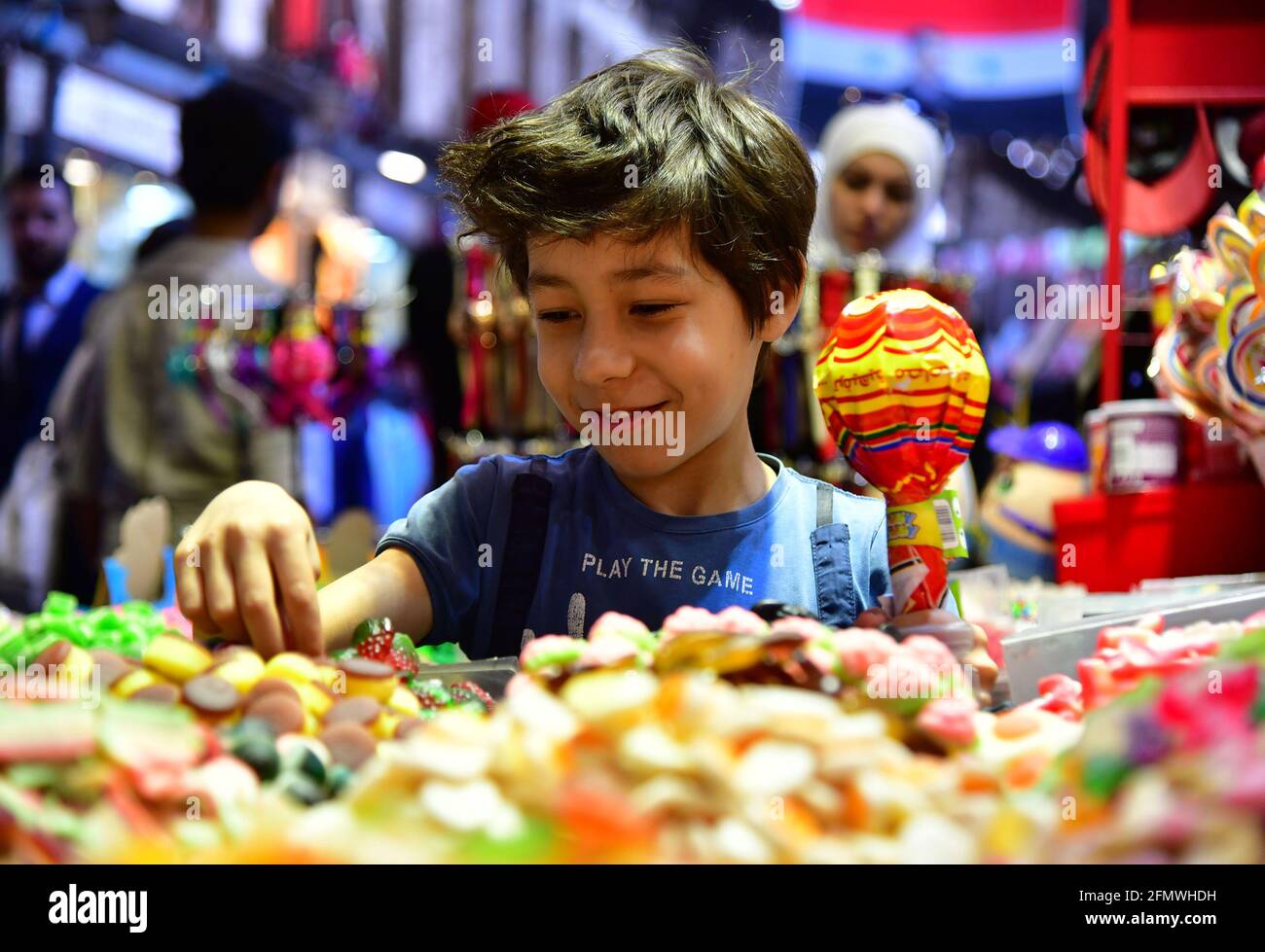Damascus, Syria. 11th May, 2021. A boy chooses candies at a market in ...