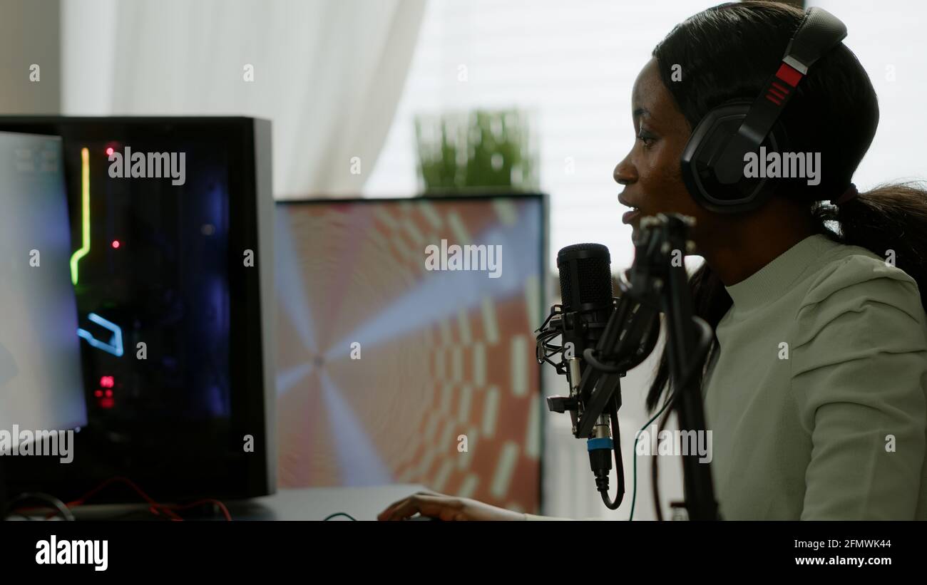 African gamer checking sound mixer sitting in gaming room and talking ...