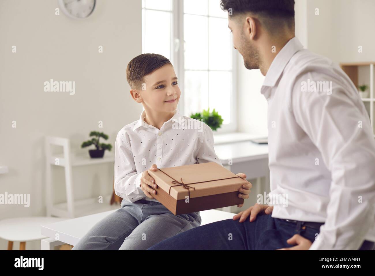 Cute little boy son gives dad a gift in a gift box in honor of his ...