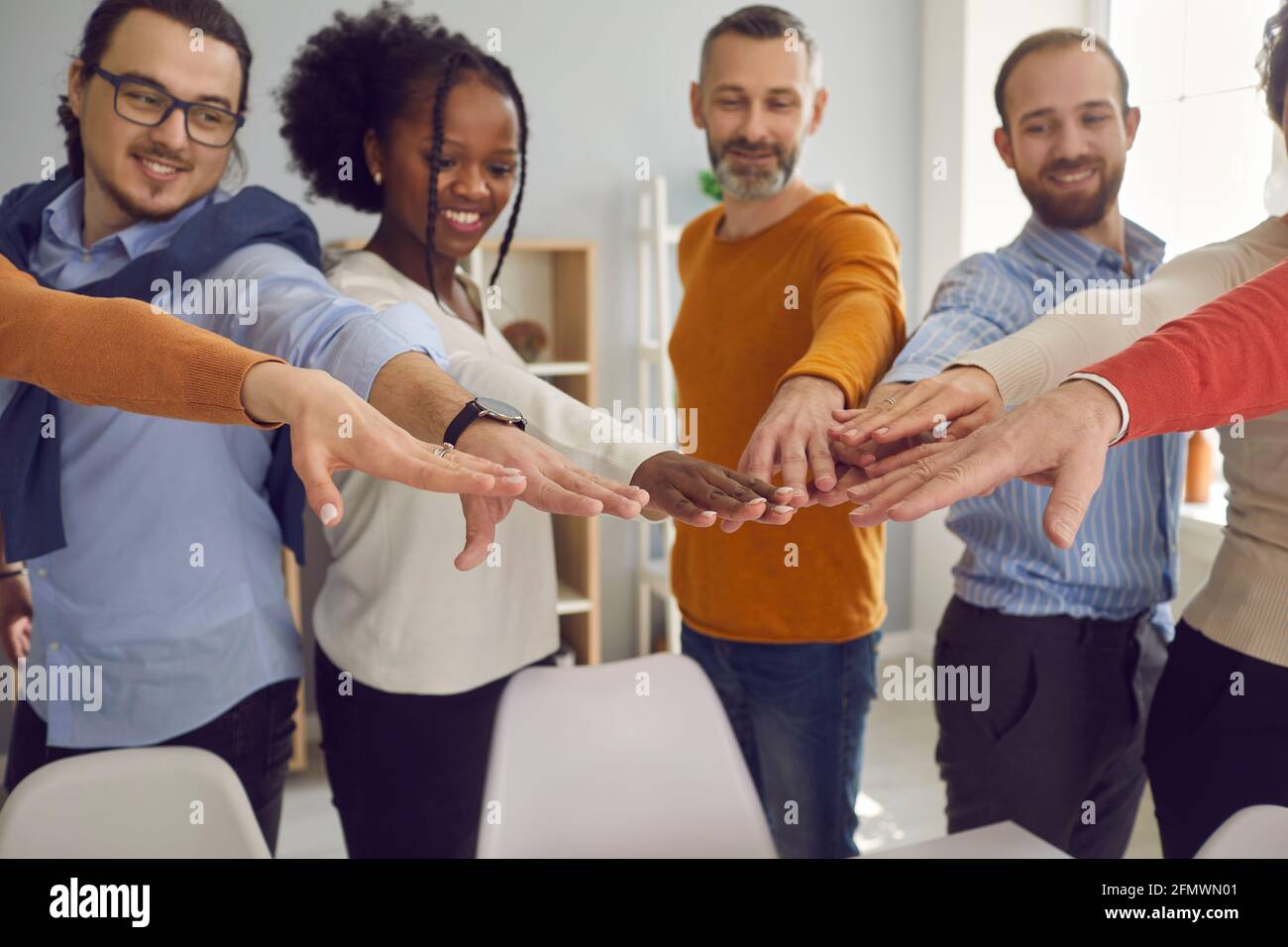 Happy smiling diverse business team members join their hands after ...