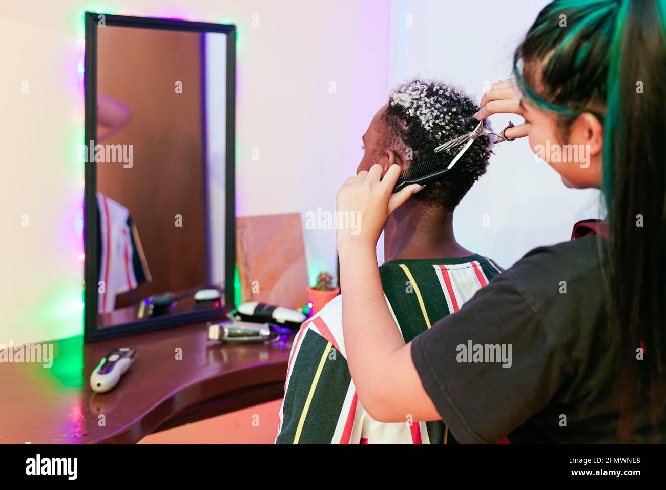 Young Asian woman barber cuting black an white hair customer. Beautiful ...