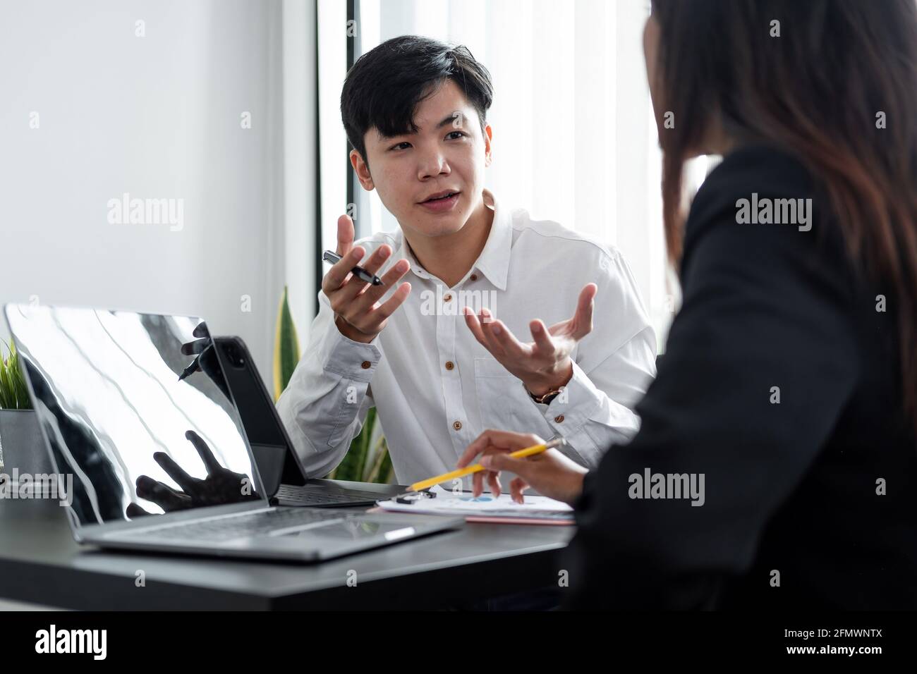 Young asian male mentor coach worker talking to female coworker ...