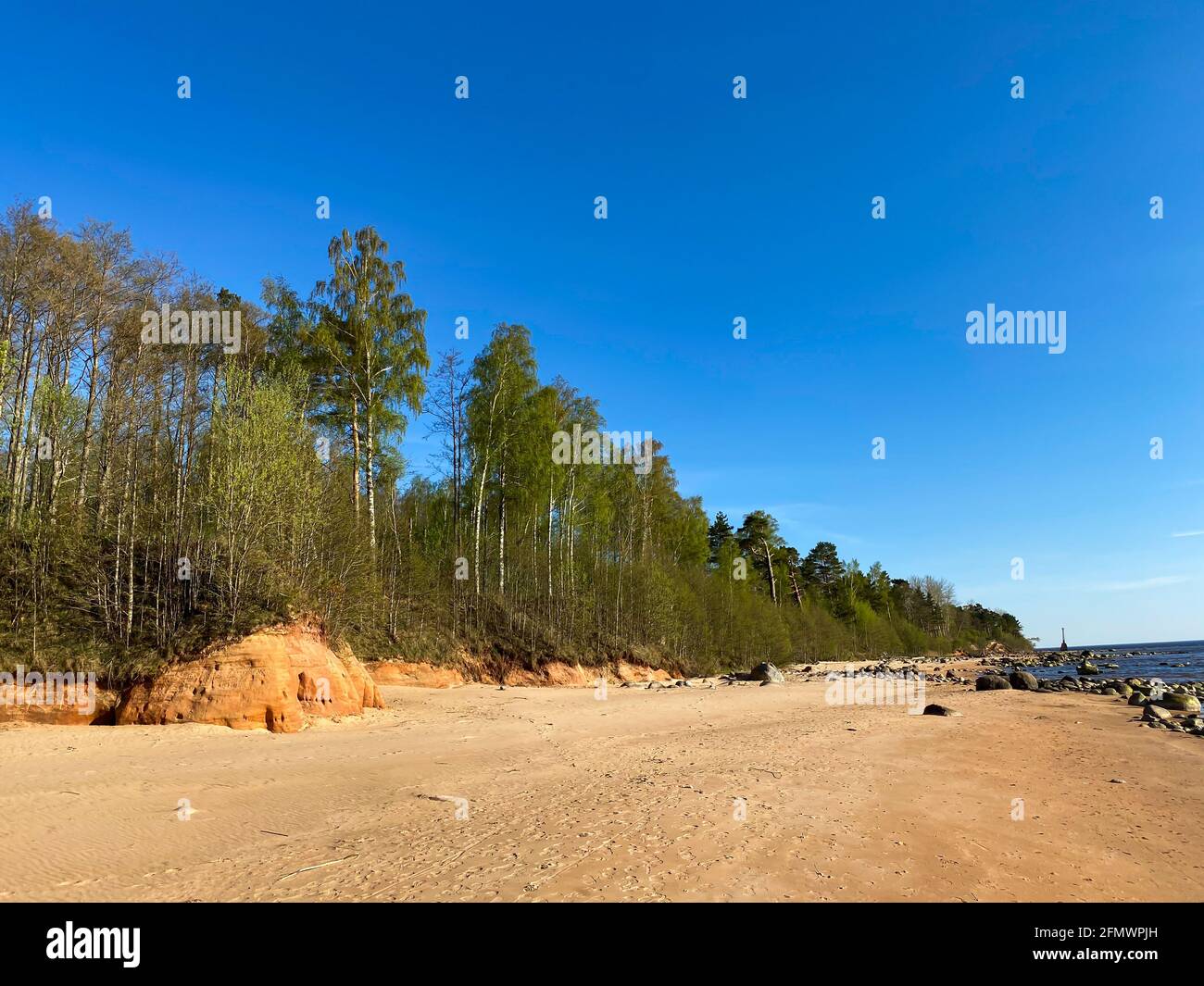 sea shore on a summer beach with blue water waves and sand with rocks ...