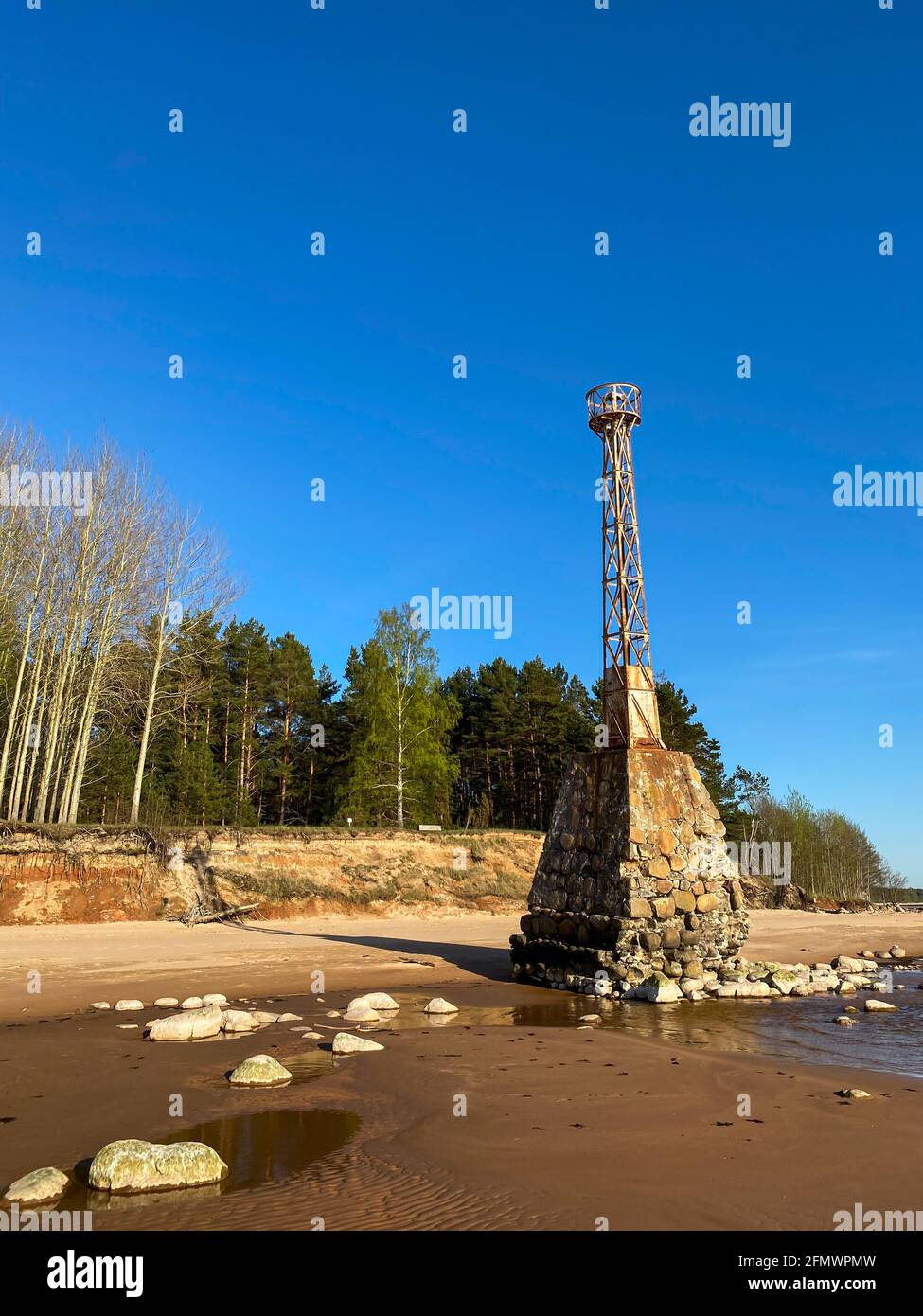 old abandoned metal rusty lighthouse with a large stone foundation on ...